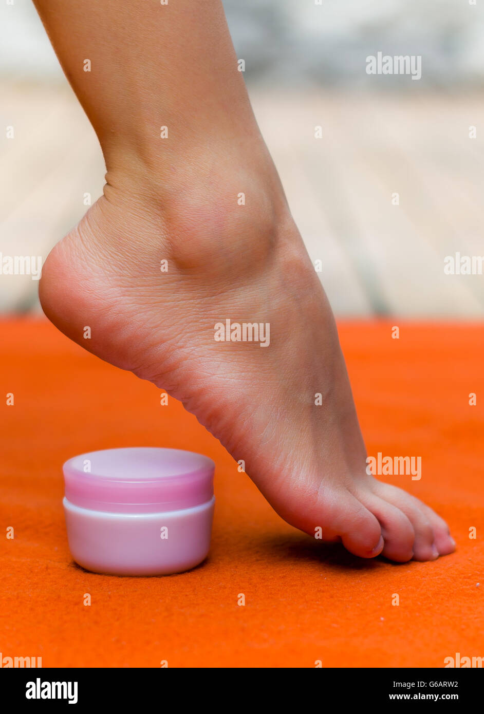 Beautiful feet standing on her toes with a pot of cream, pink color of ...