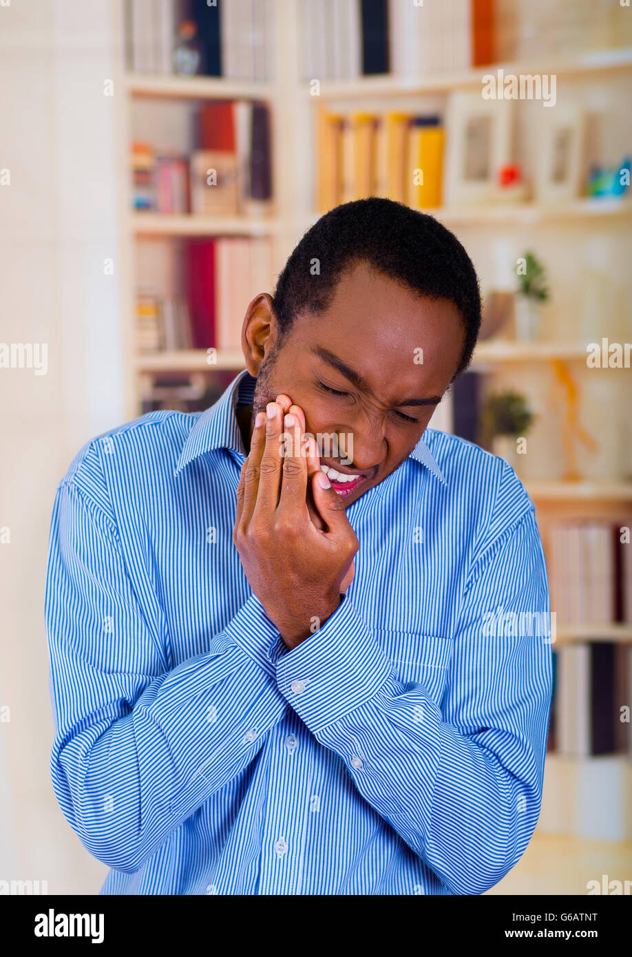 Man with blue shirt, stand up and holding his cheek with both hands ...
