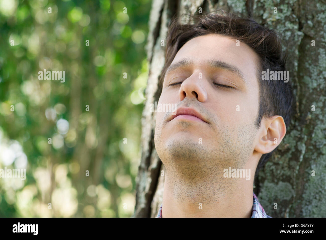 Man leaning against tree lost in thought Stock Photo - Alamy