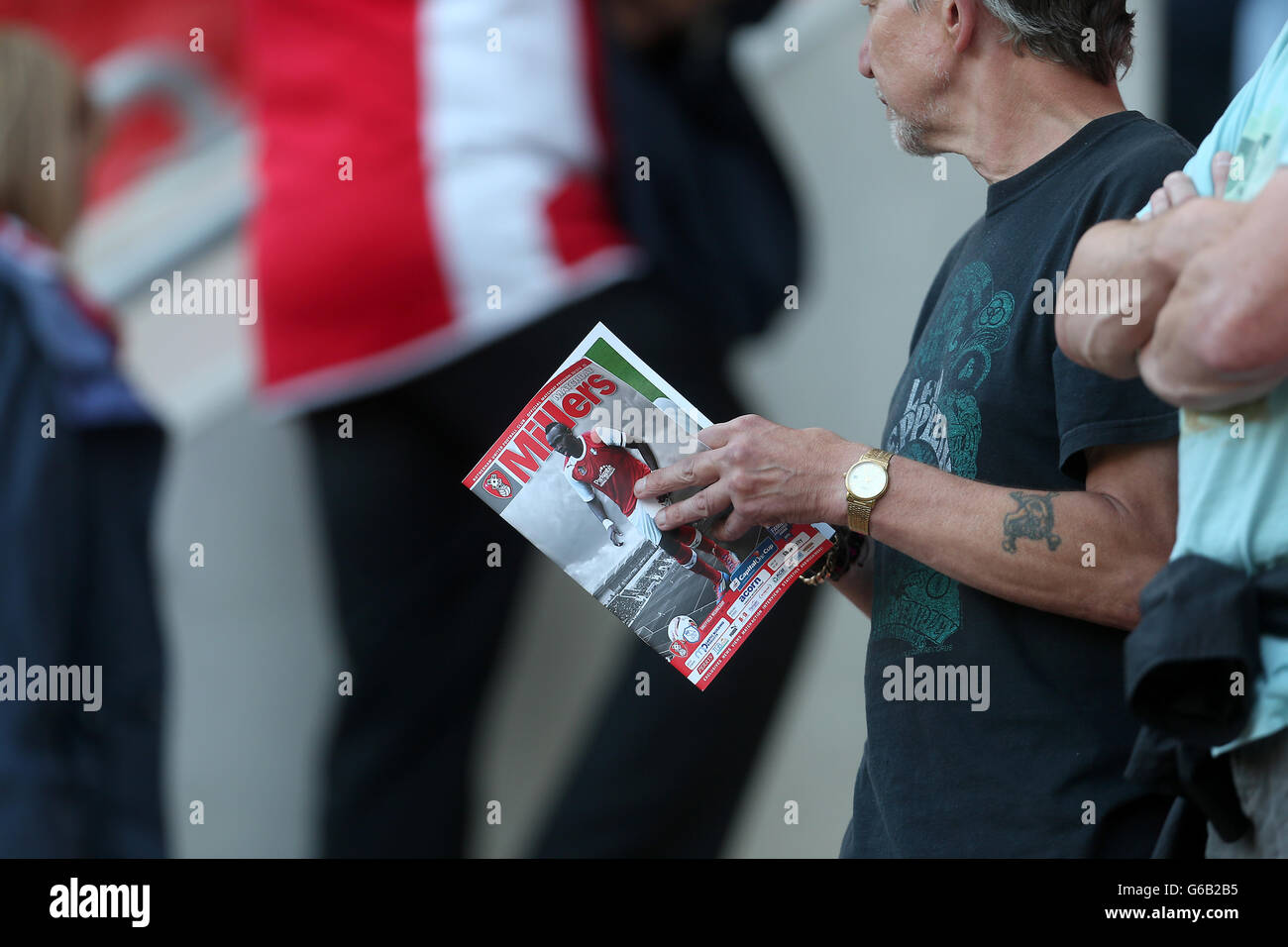 Football fans read the match day programme in the stands Stock Photo ...