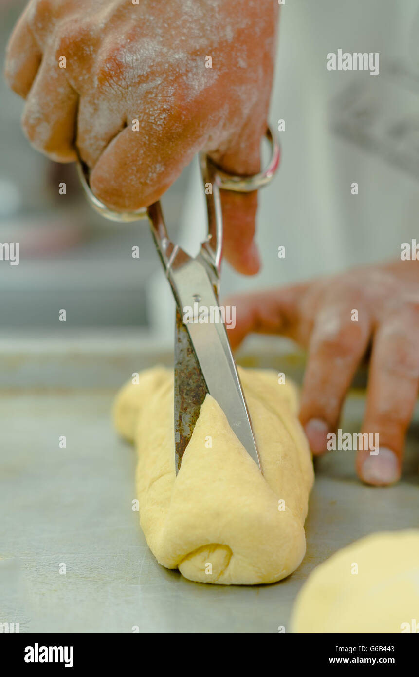 Bakers hands holding scissors above prepared bread dough roll Stock ...