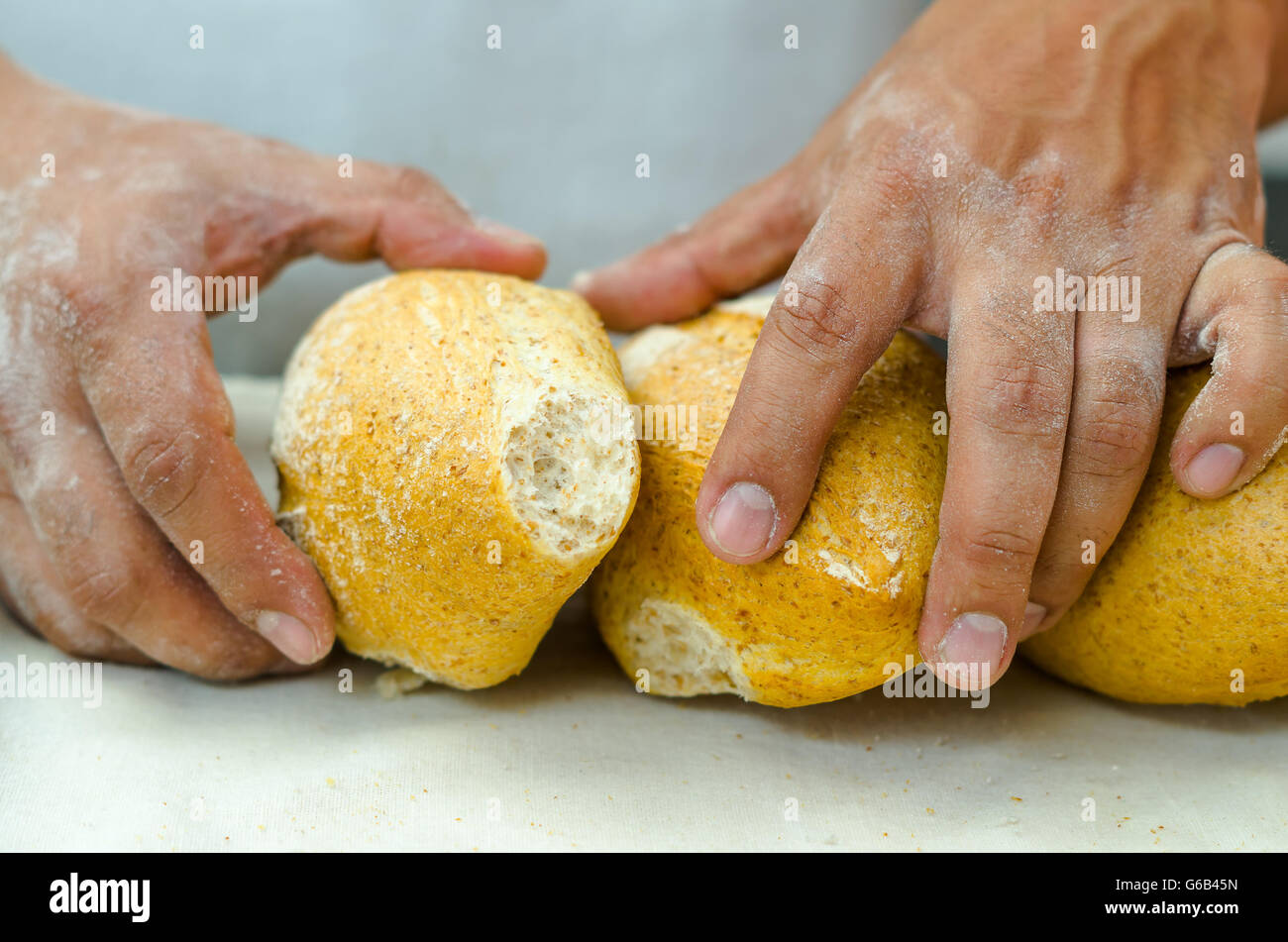 Bakers hands stacking fresh delicious buns of bread against each other ...