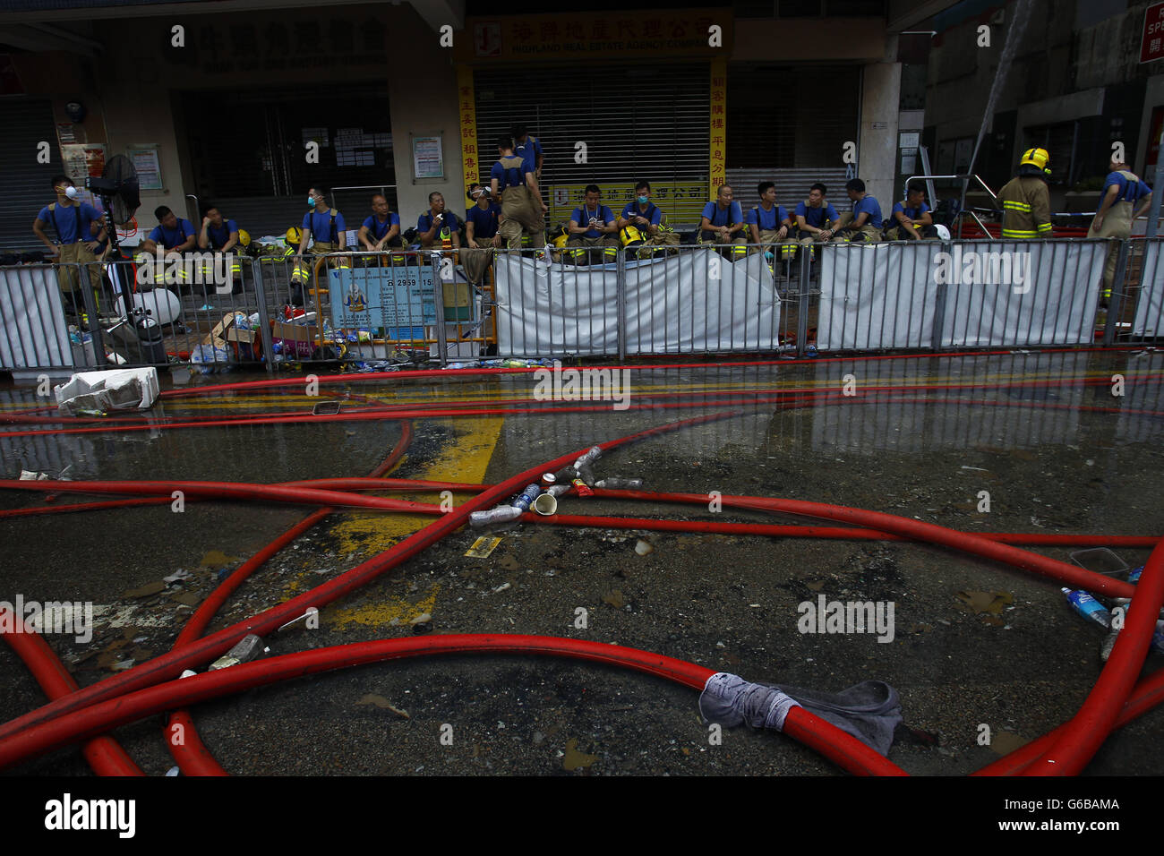 Firefighers rest beneath the building which is adjacent to the burning ...