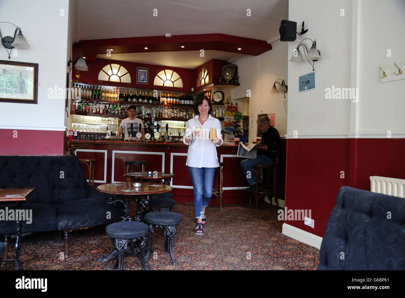 A middle aged woman carrying drinks in a Pub Stock Photo - Alamy