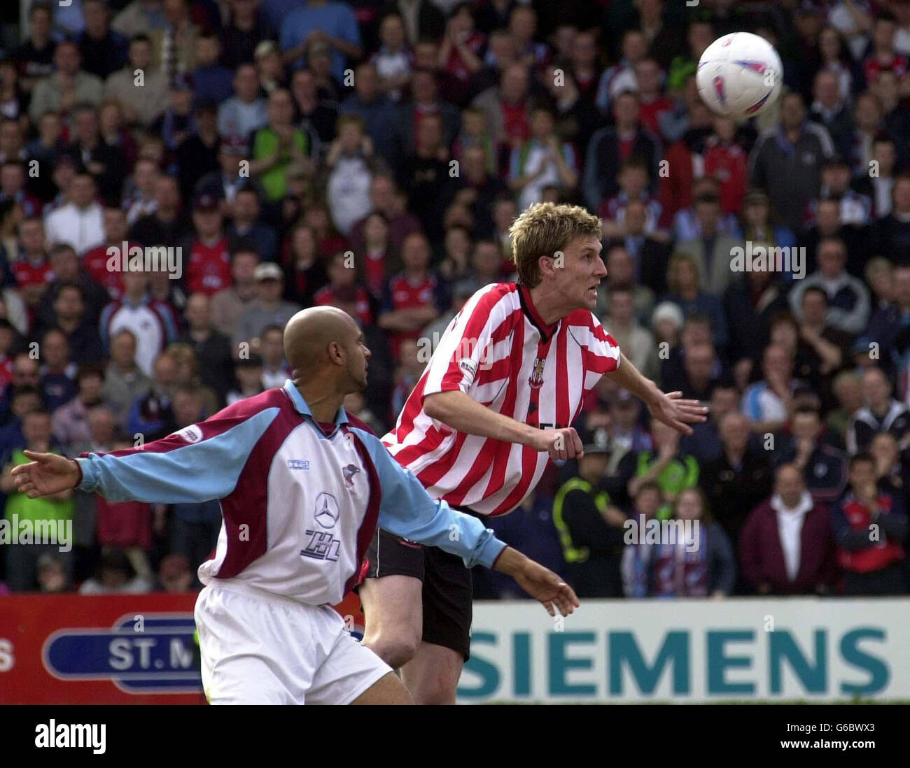 Lincoln's Ben Futcher (r) heads clear, watched by Scunthorpe's Martin ...