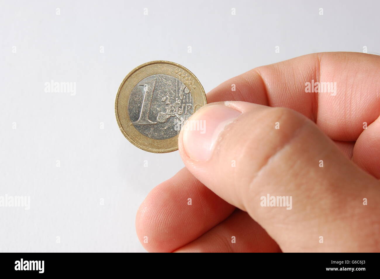 A male hand holding €1 coin Stock Photo - Alamy