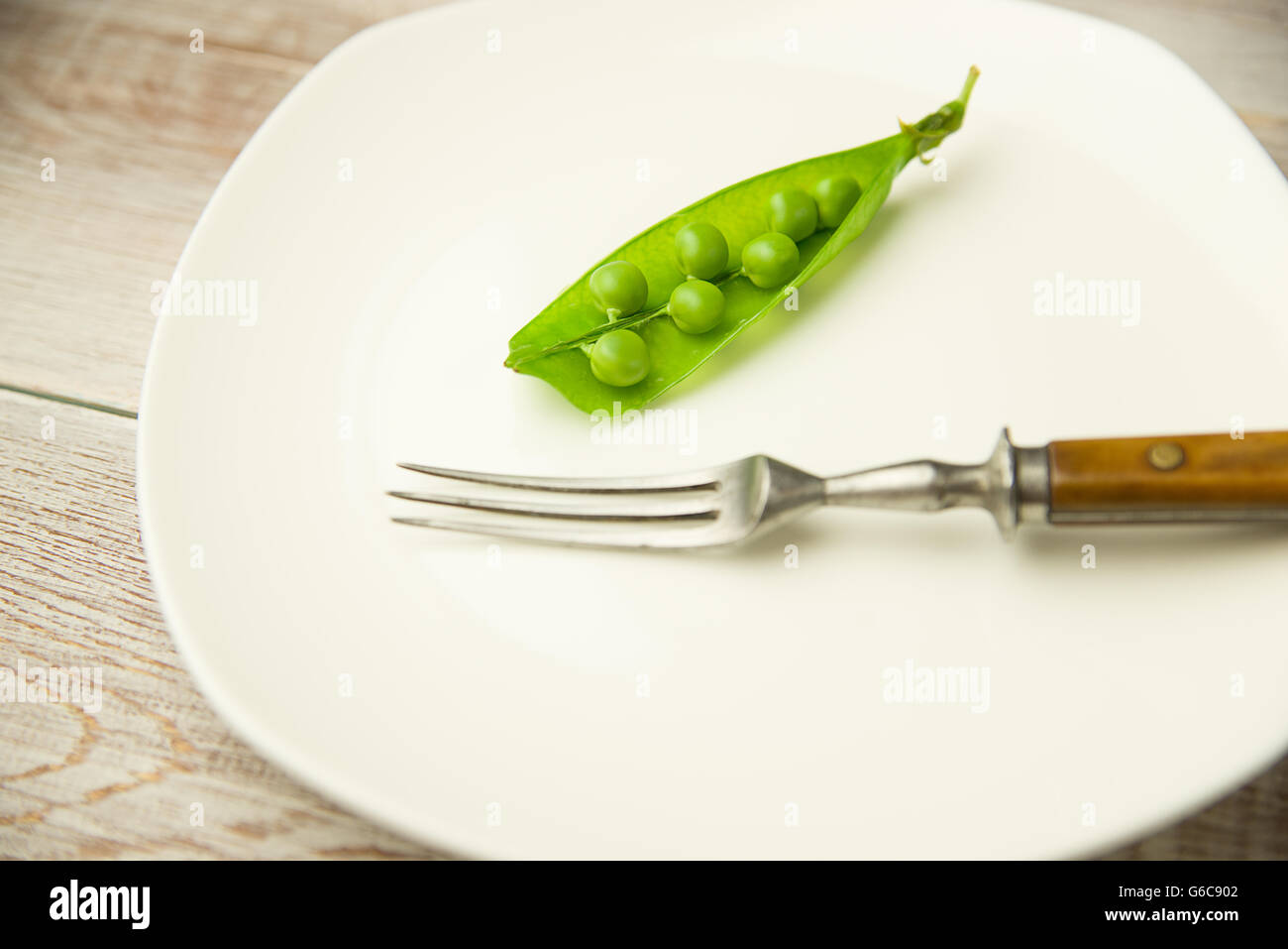Green pea pod and fork on the white plate Stock Photo - Alamy