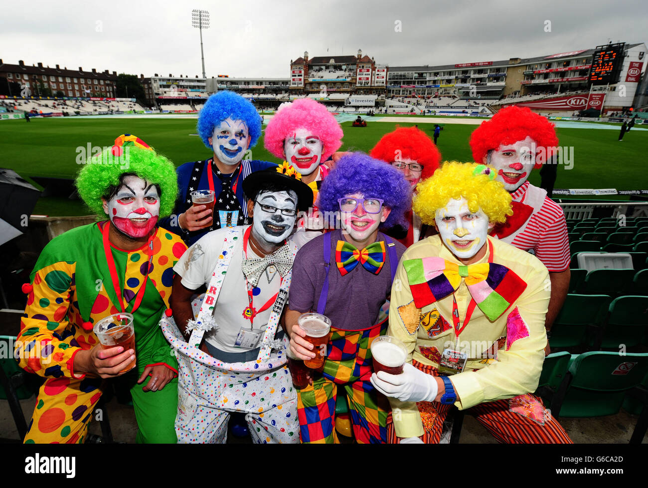 Spectators dressed as clowns wait for the rain to stop during day four ...