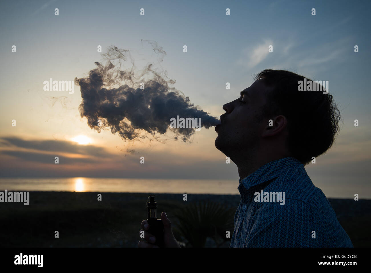 Man smoking vaping e-cigarette vape box mode over golden sunset Stock ...