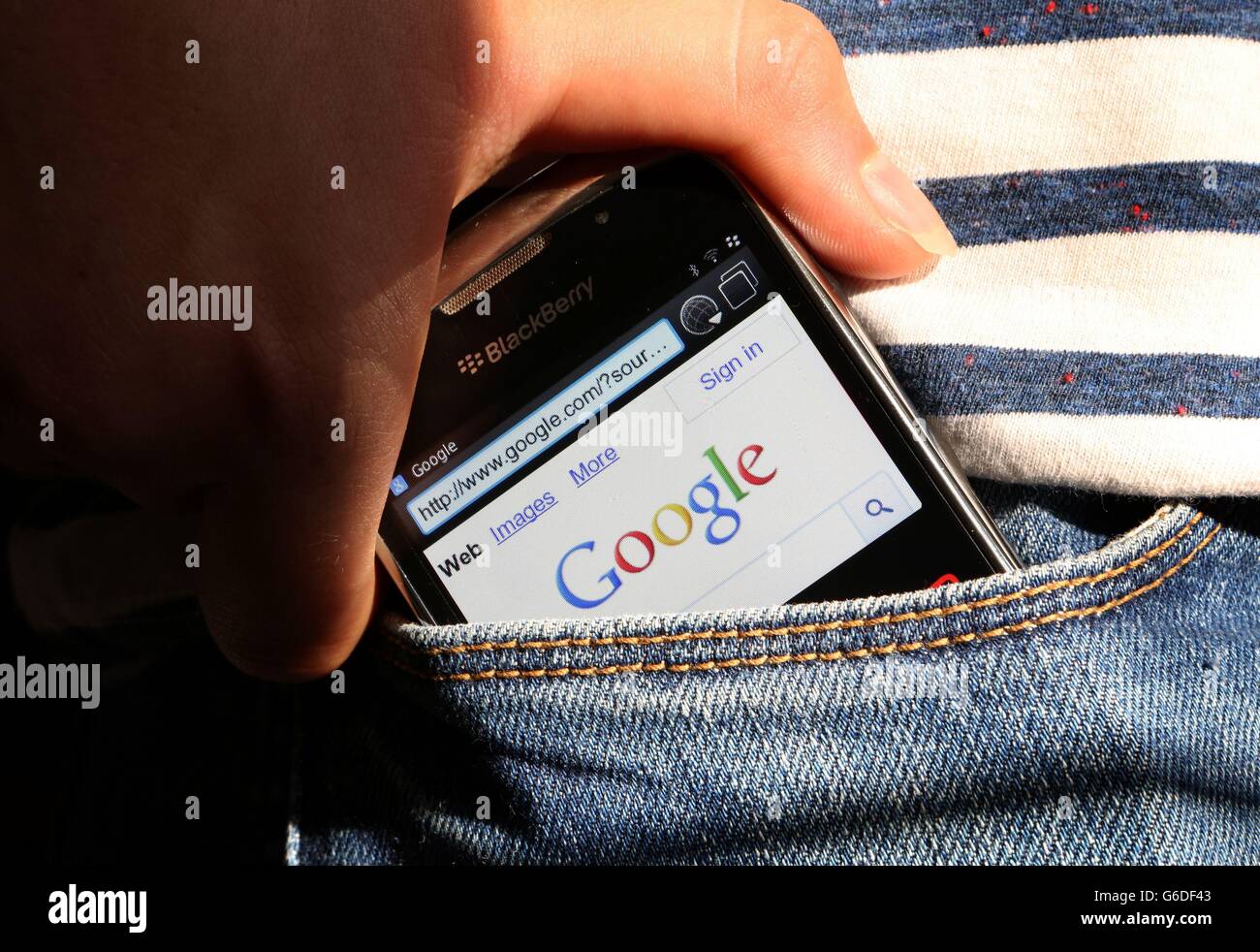 A man with a BlackBerry phone showing the Google search engine home ...