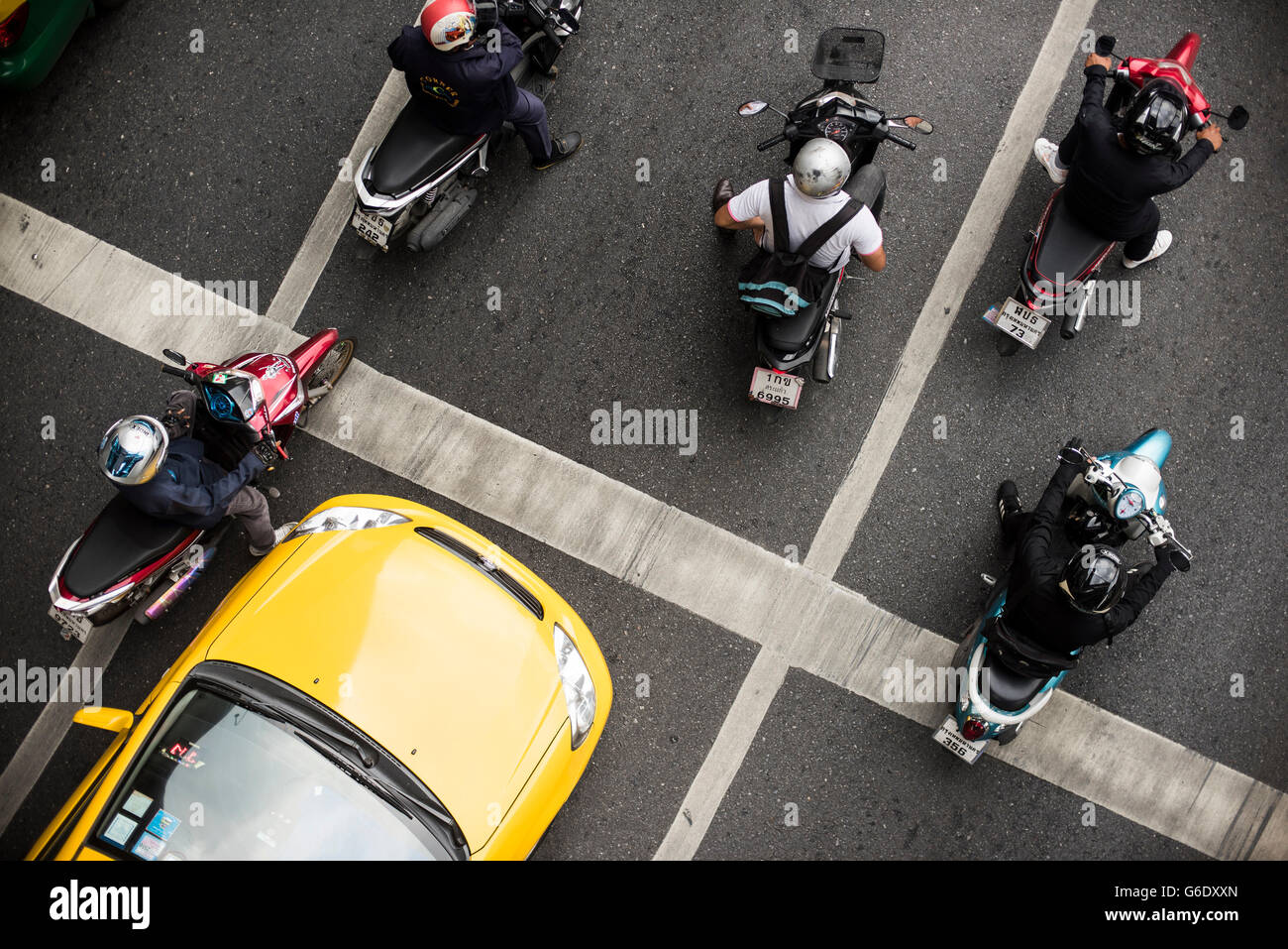 Pictured from above, motorbikes and a taxi wait at a light in downtown ...