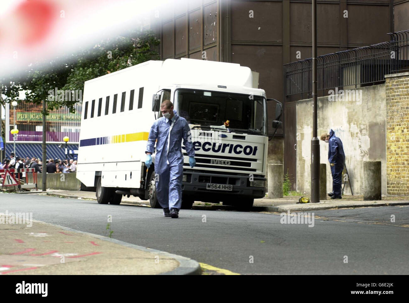Police forensics investigate the area around an abandoned prison van ...