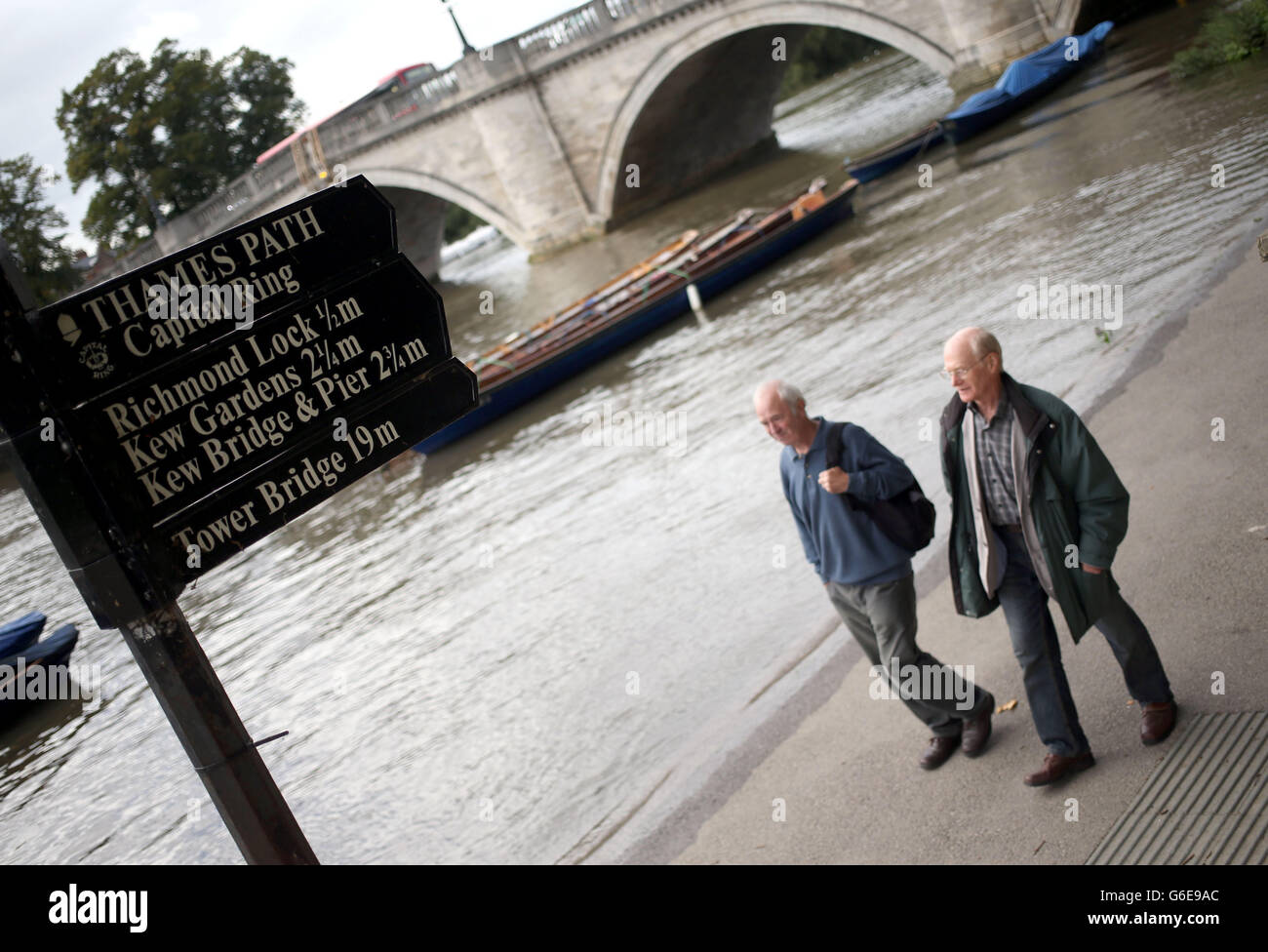 People walk past a Thames Path sign in showing the towpath along the ...