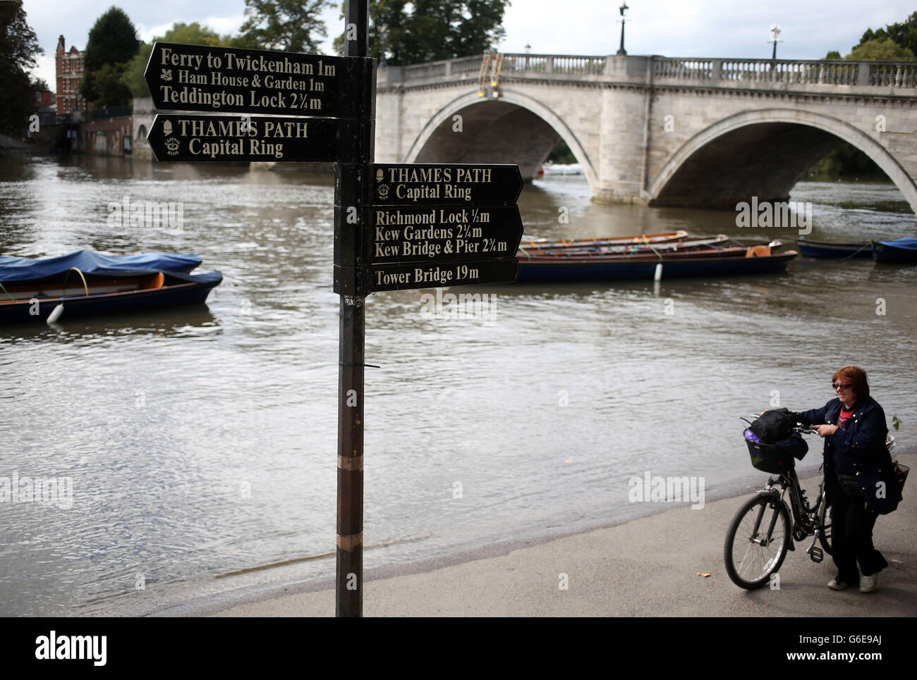 People walk past a Thames Path sign in showing the towpath along the ...