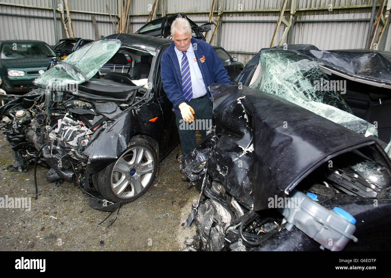 A member of staff looks at the remains of the Ford Mondeo and Audi cars ...