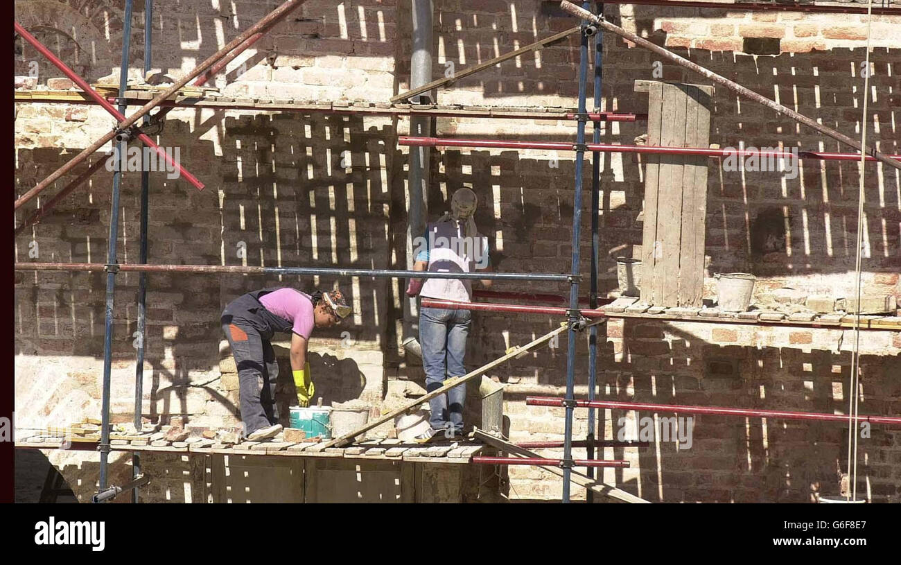 A couple of female restoration workers toil at their work, as the ...