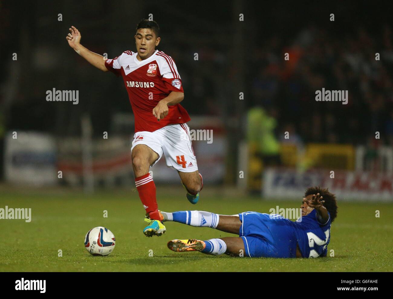 Swindon Town's Massimo Luongo (left) skips over the tackle of Chelsea's ...