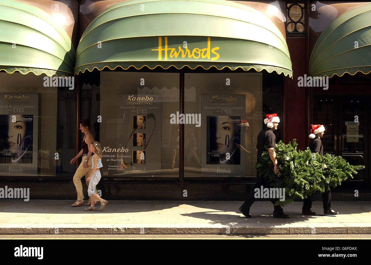 Two Harrods employees carry a Christmas tree past the famous London ...