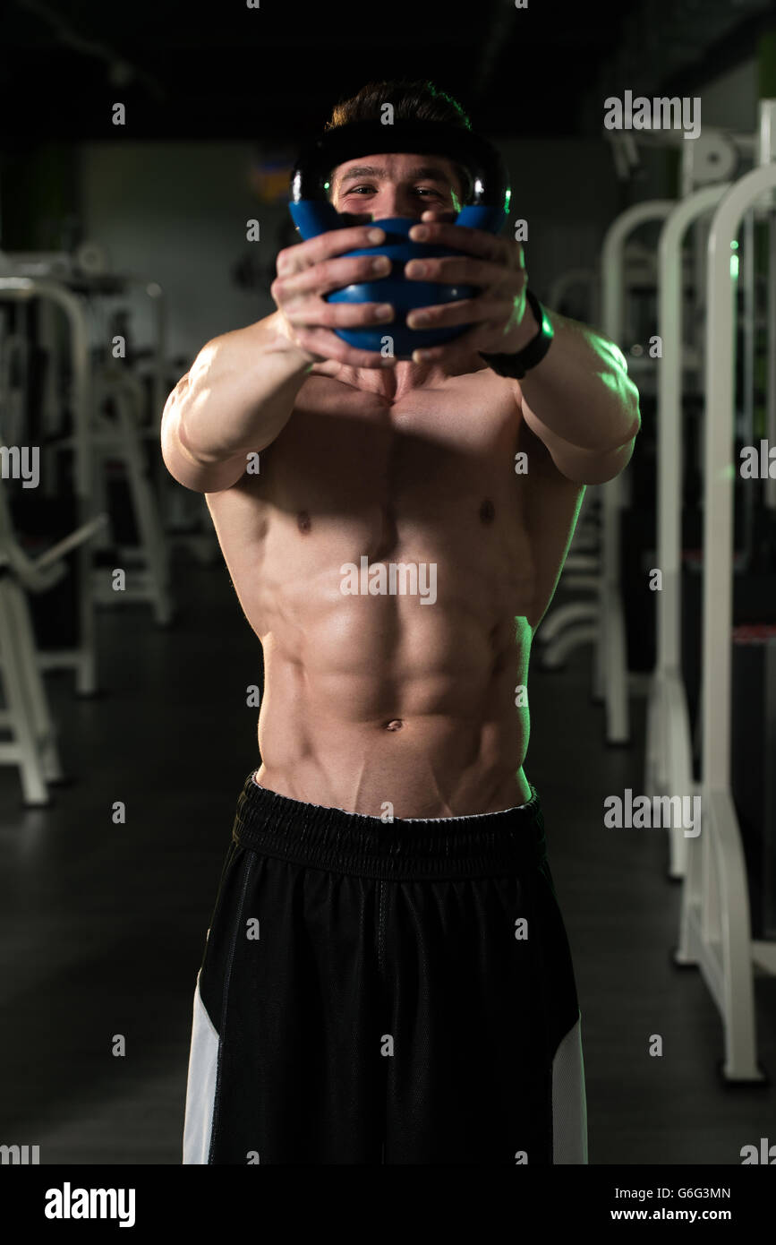Young Man Exercising With Kettle Bell And Flexing Muscles - Muscular ...