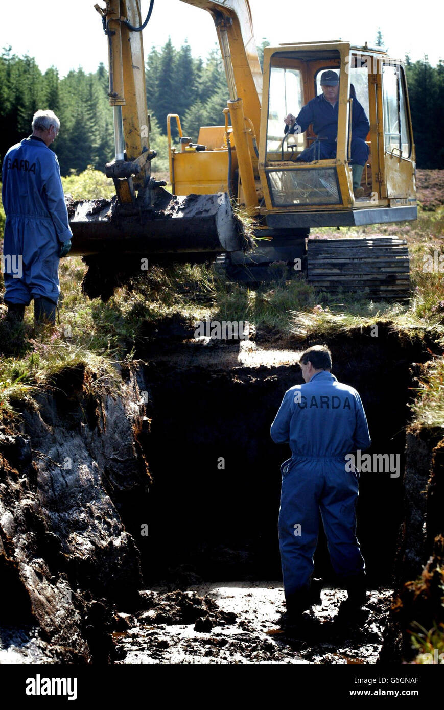 A Garda police officer studies the contents of a bucket, during a dig ...