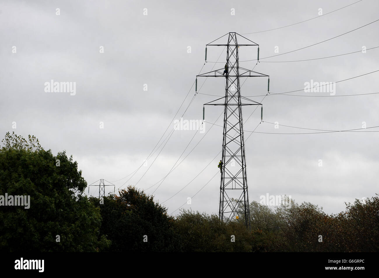 Workmen climb an electricity pylon to carry out maintenance in ...