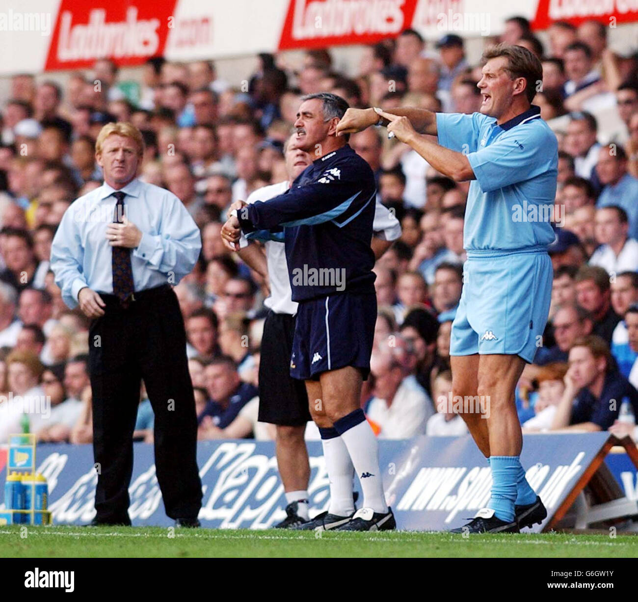 Spurs manager Glenn Hoddle gestures the time to his players (right) as ...