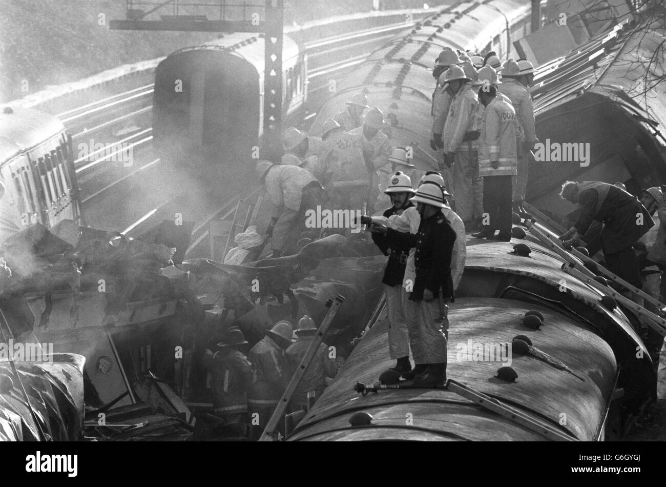 Firemen standing on top of derailed carriages as their colleagues work ...