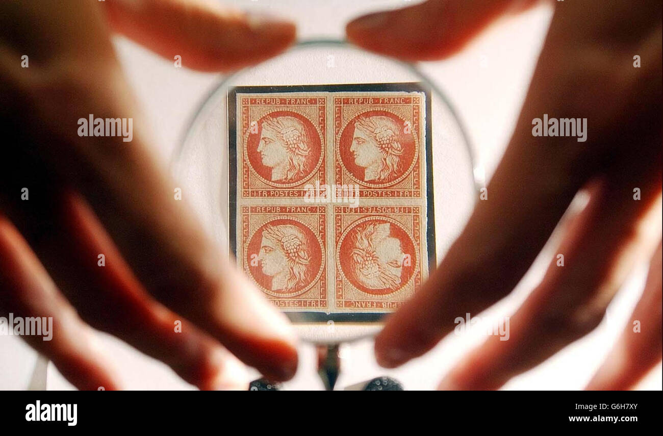 A stamp expert at Spink's Auctioneers in Central London, examines a set ...
