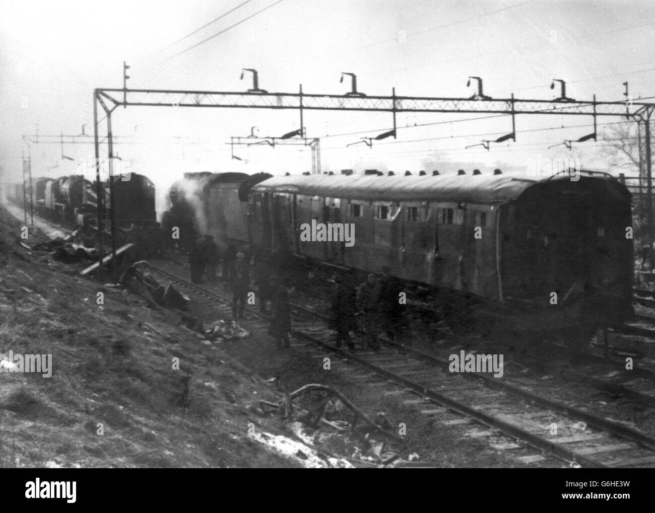 Debris still lines the track and one of the shattered coaches is being ...