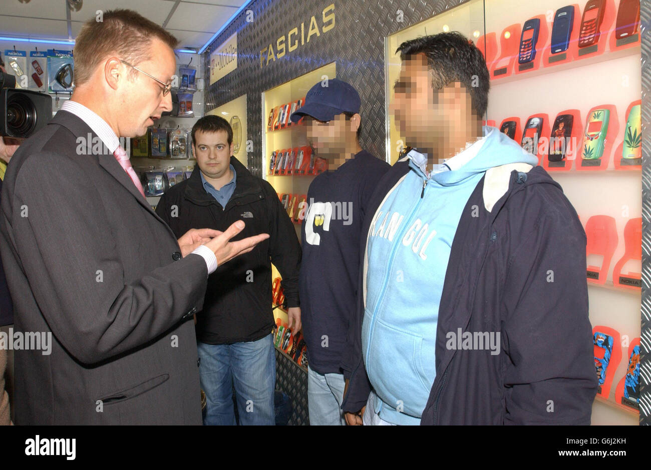 Wandsworth detectives question a mobile phone shop manager (right) and ...