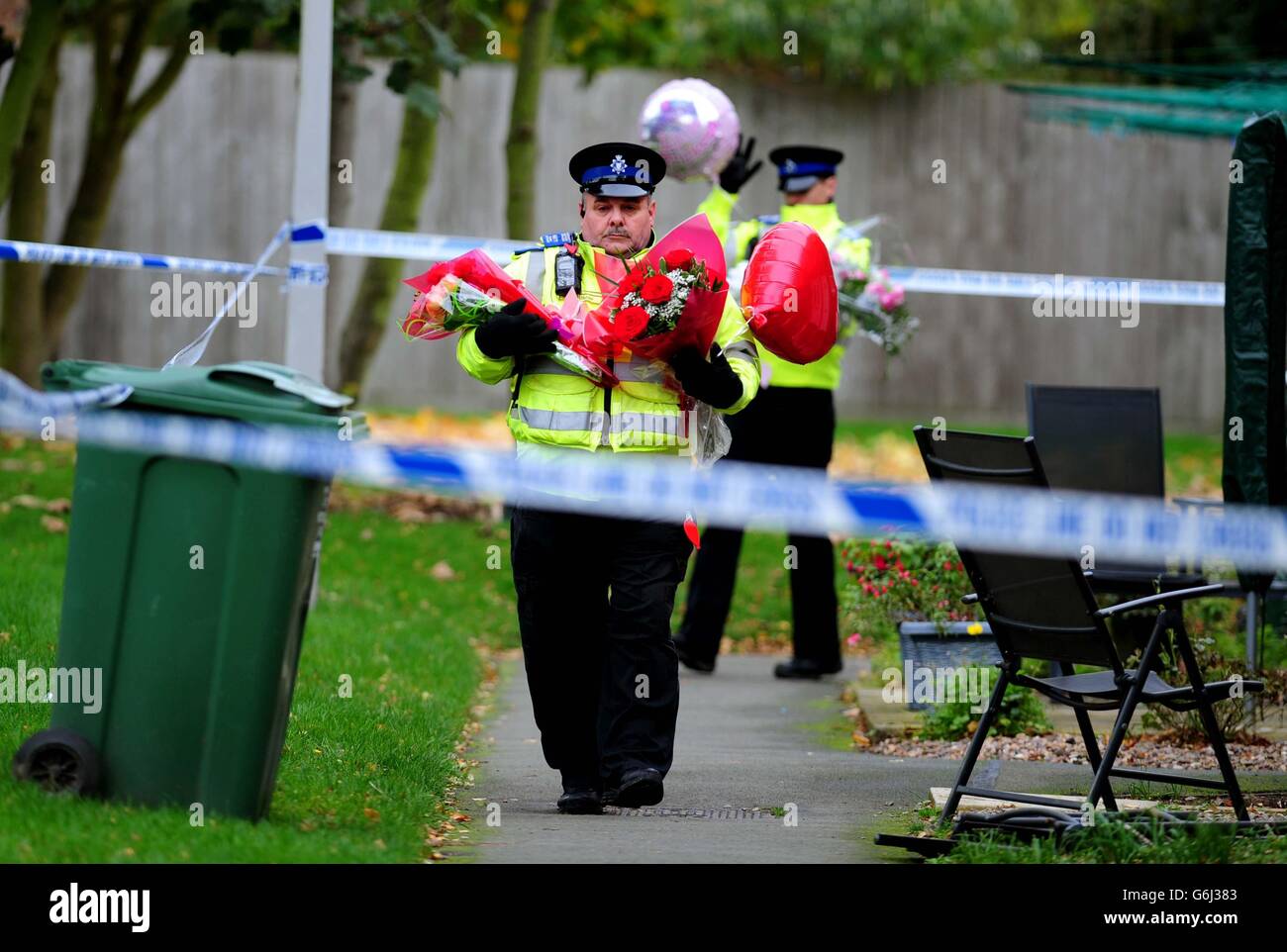 Police carry floral tributes outside the home in Rowena Court in ...