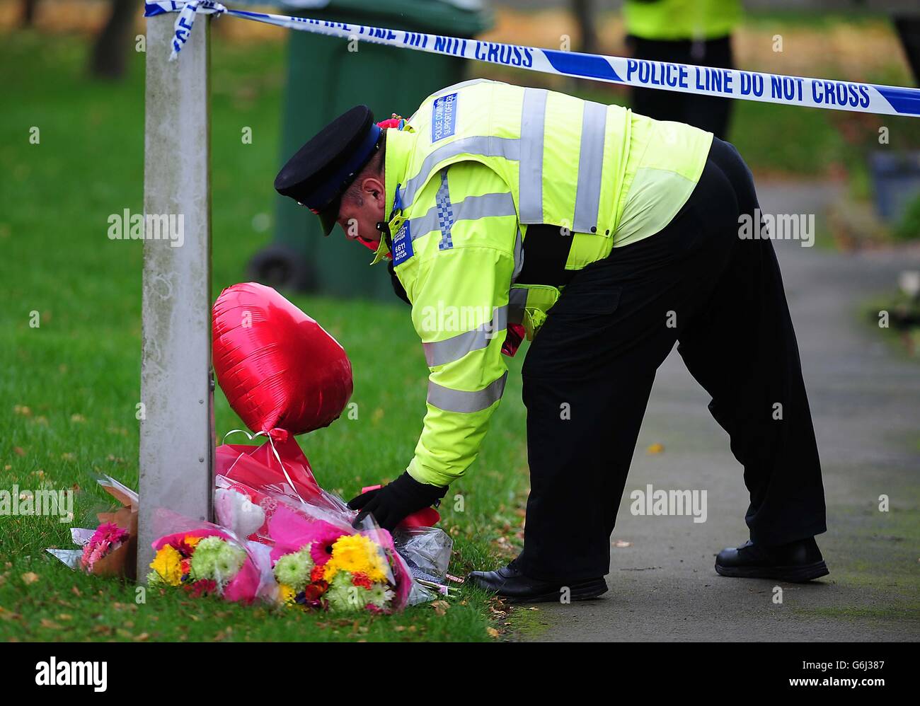 Police carry floral tributes outside the home in Rowena Court in ...