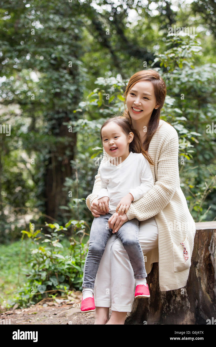 Asian Mother and Daughter Smiling, Sitting on the Tree Stump in the ...