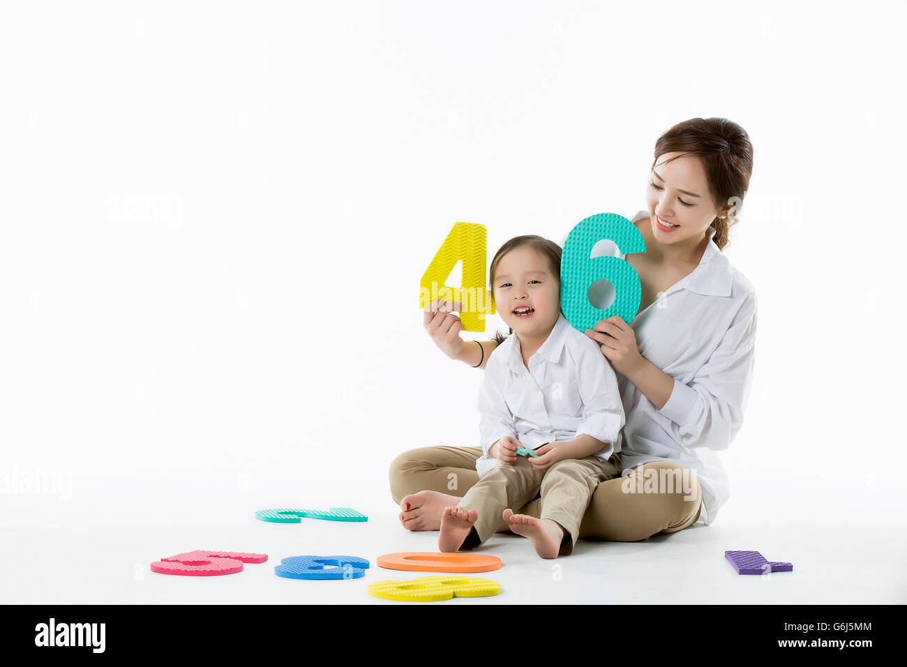 Little Asian Girl Sitting on Mother's Lap, Playing with Sponge Digits ...