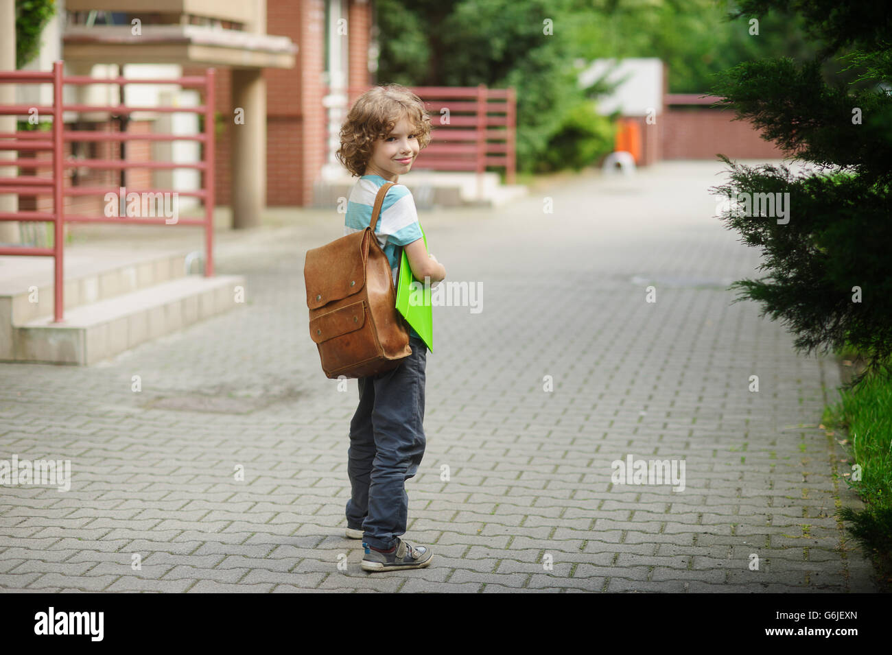 Chappie of 8-9 years is in the school yard. Holds the bright folder in ...