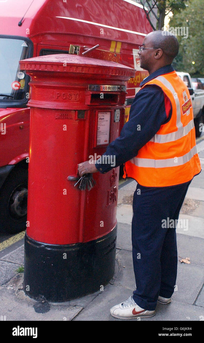 A Royal Mail worker unlocks a post box in central London, as activity ...