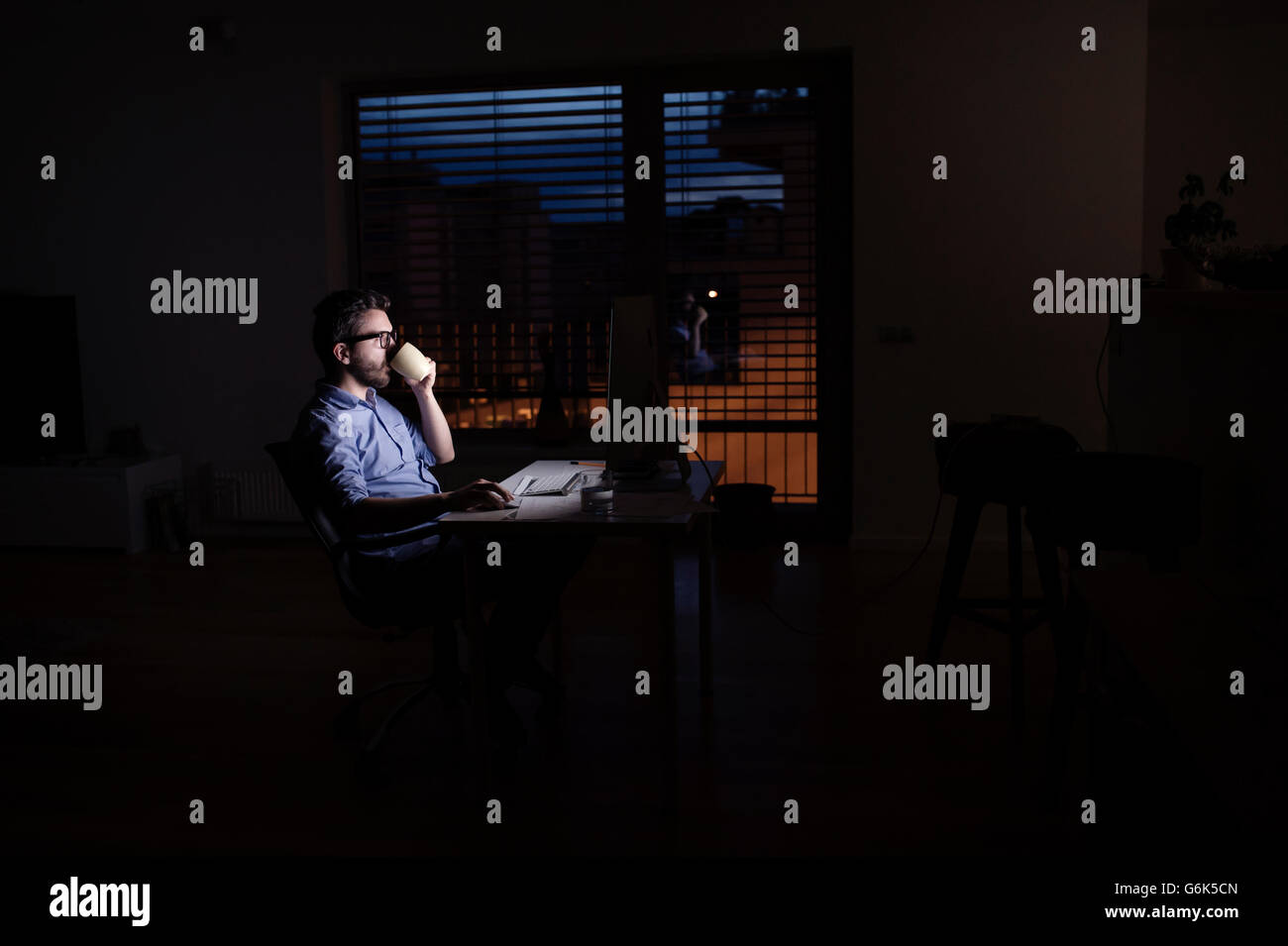 Man working at computer and drinking coffee at night Stock Photo - Alamy