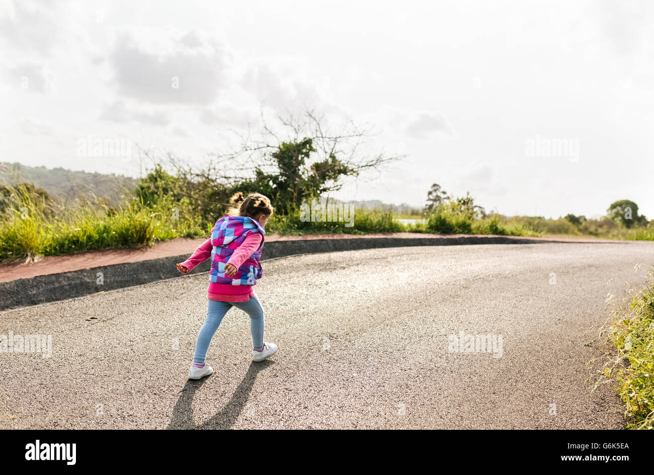 Back view of little girl walking on country road Stock Photo - Alamy