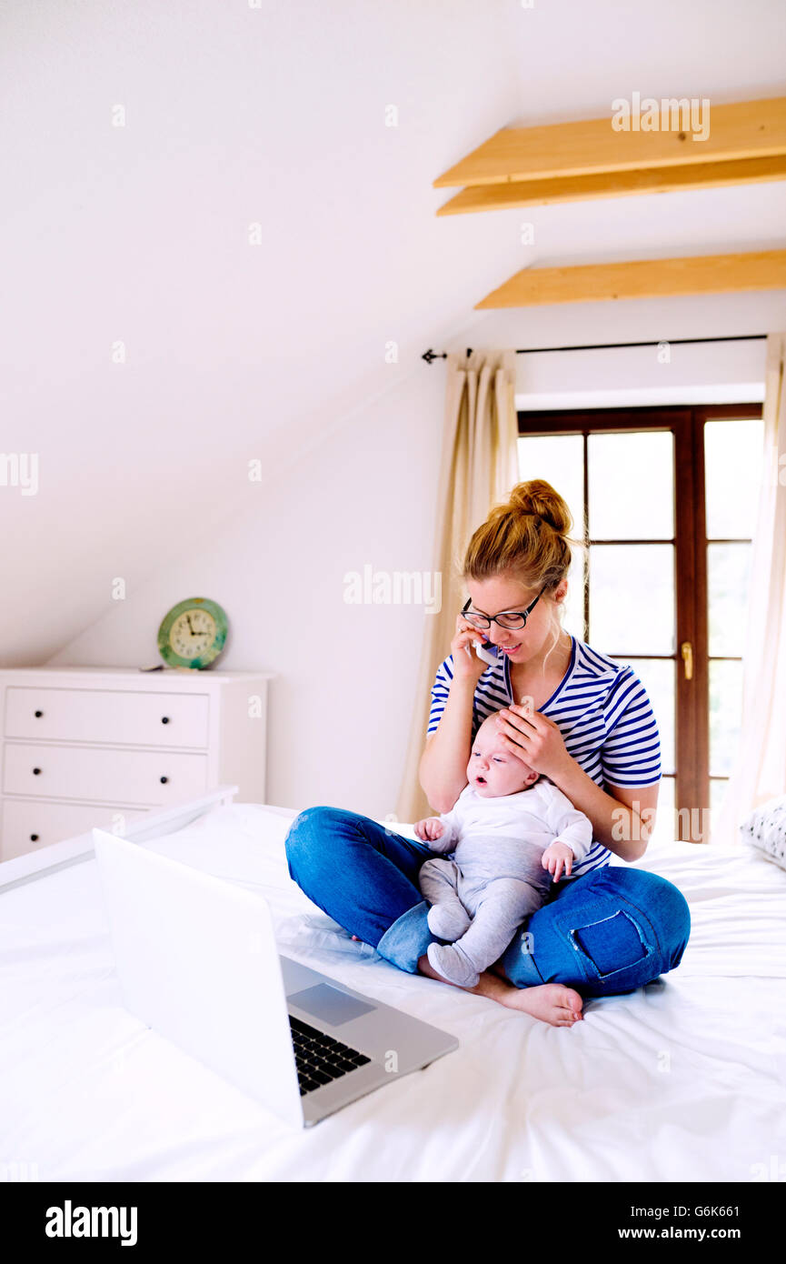 Mother with baby at home working with laptop Stock Photo - Alamy