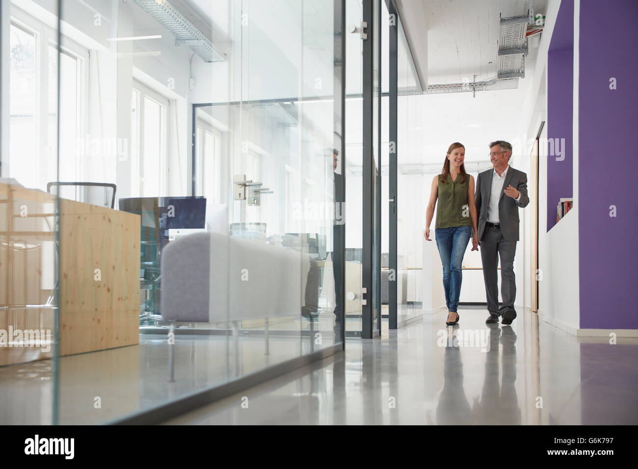 Businessman and woman walking down office corridor Stock Photo - Alamy