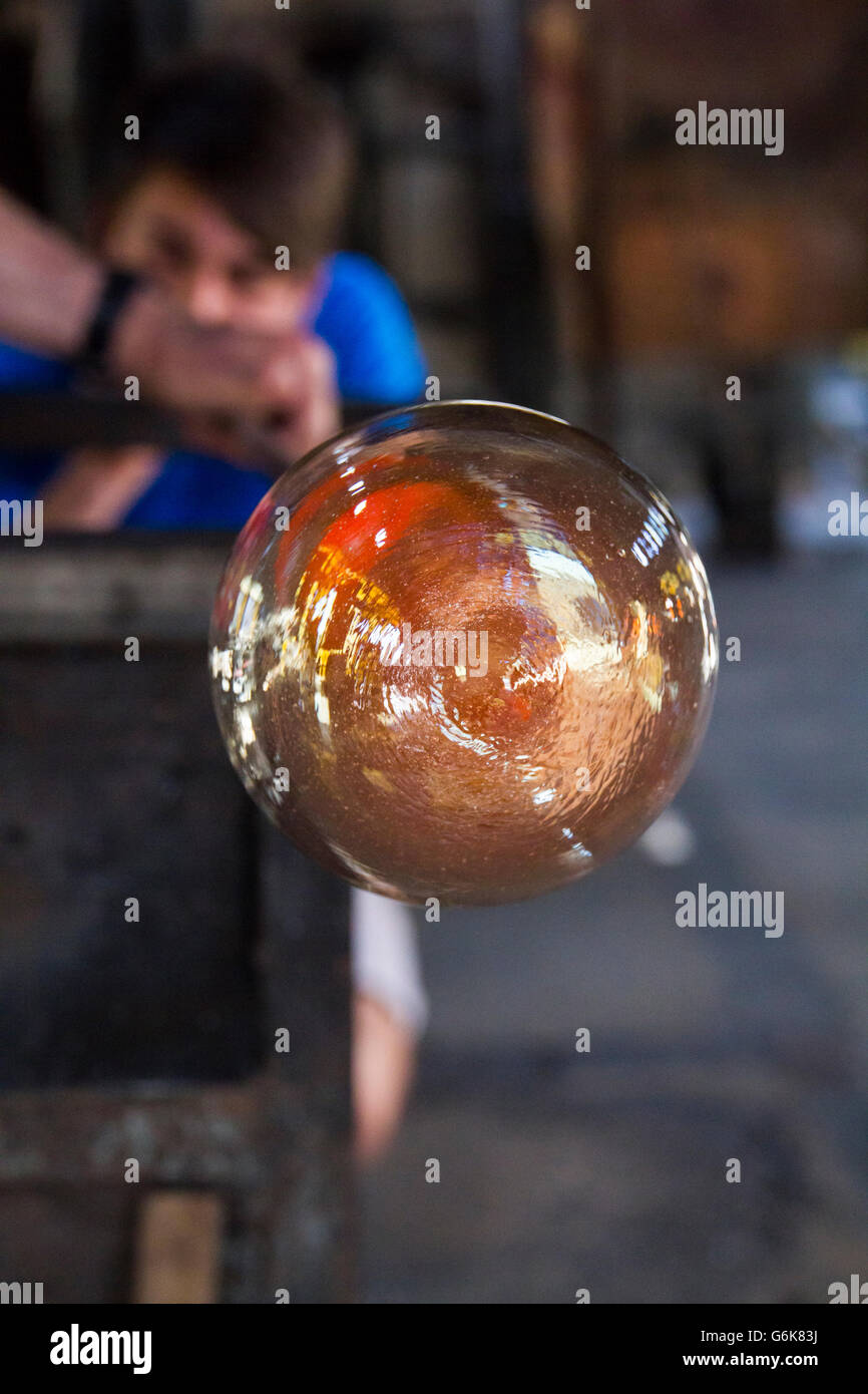 Man blowing molten glass with a tube in a factory Stock Photo - Alamy