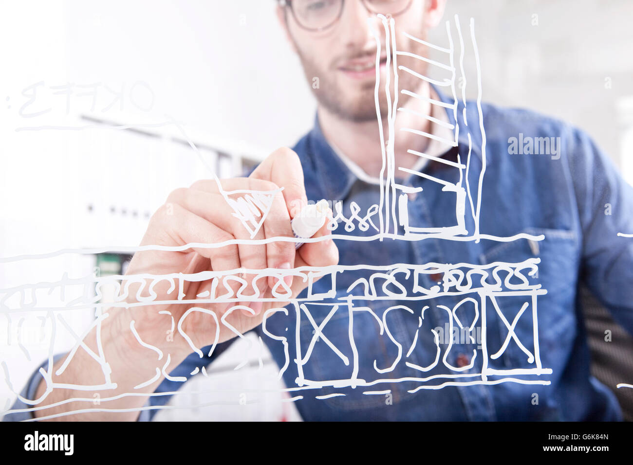Man drawing on glass pane in an office Stock Photo - Alamy