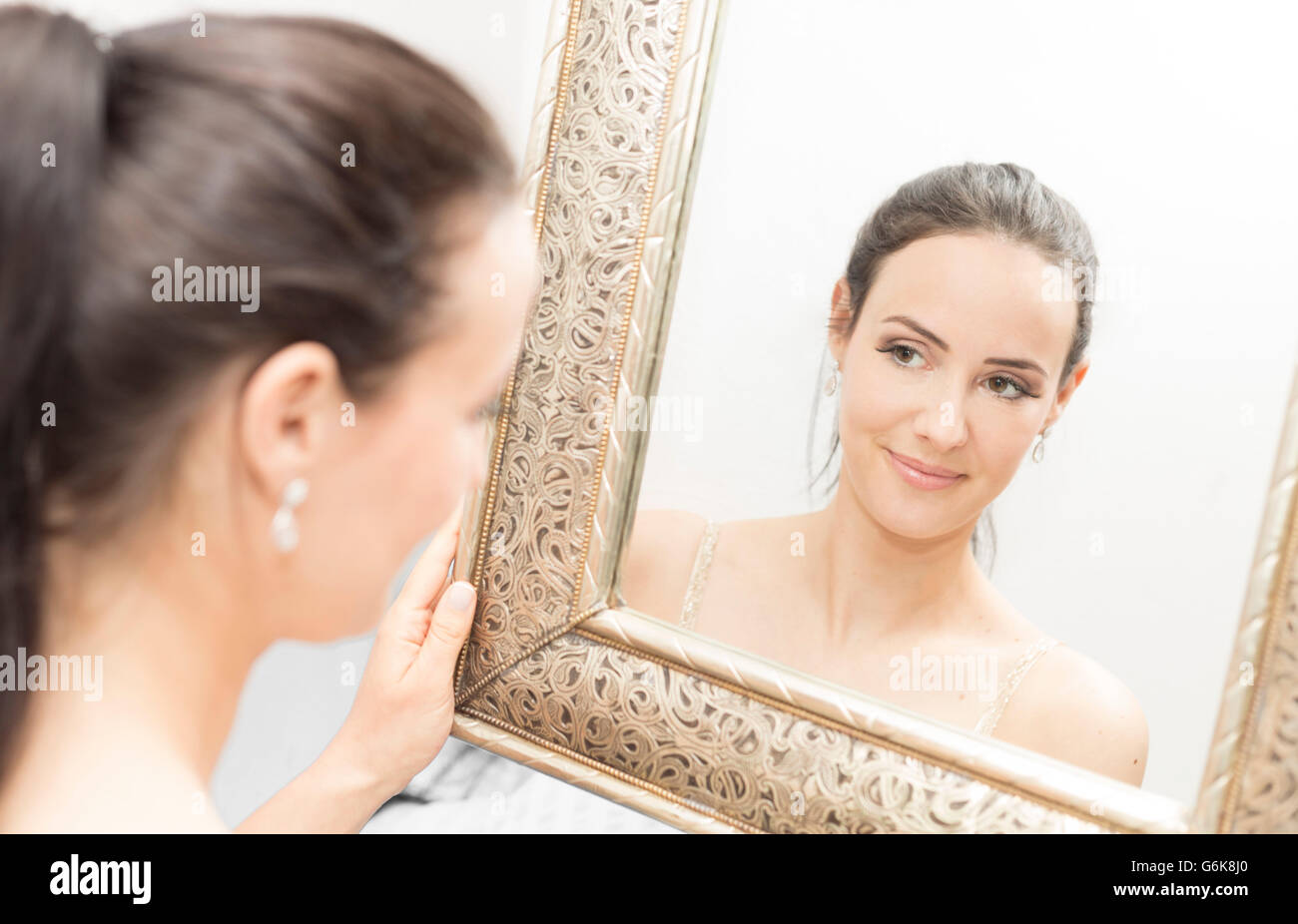 Smiling bride looking in mirror Stock Photo - Alamy