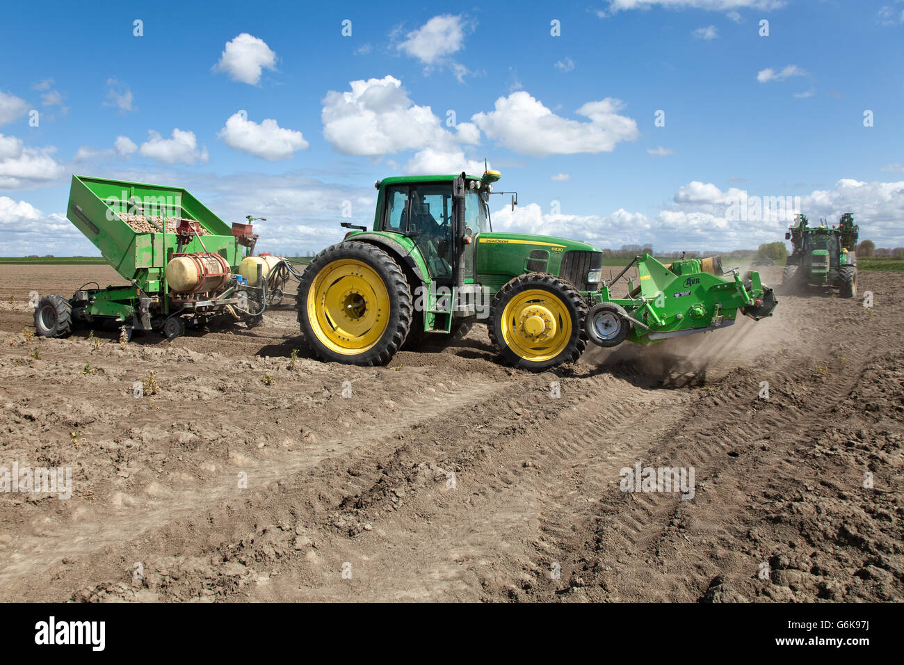 Farmer is planting dutch potatoes with his green tractor on his land ...