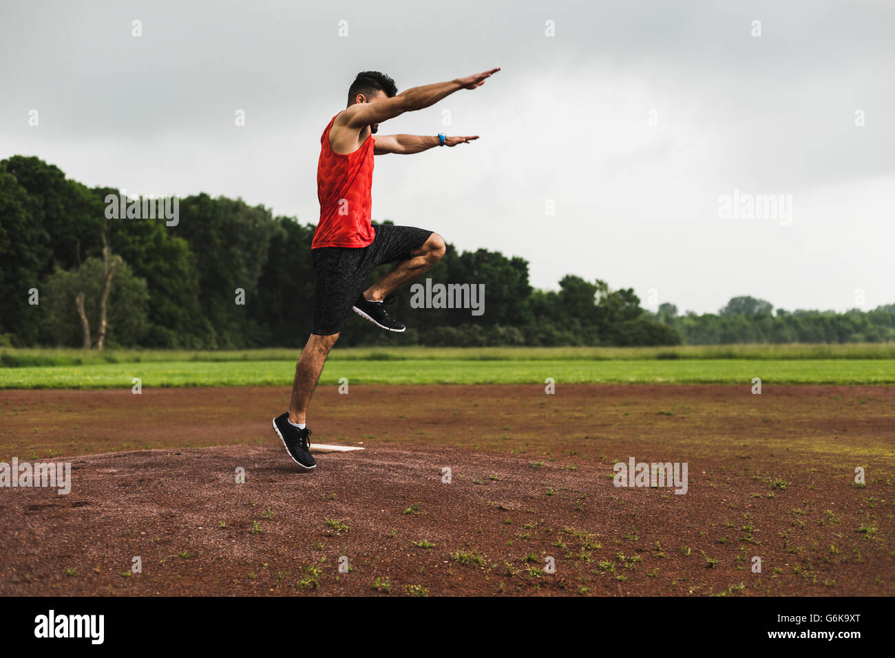 Athlete jumping on sports field Stock Photo - Alamy
