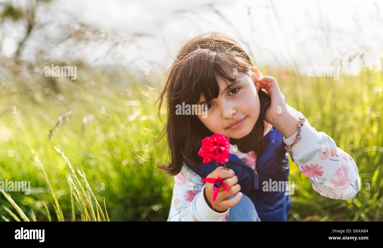 Portrait of little girl with red flower in nature Stock Photo - Alamy