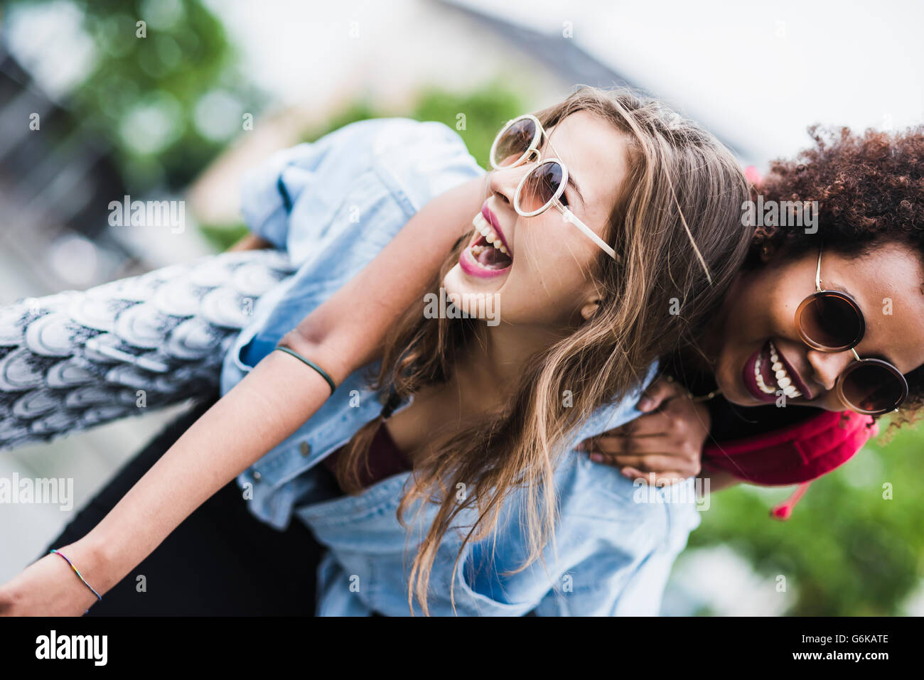 Laughing woman giving her friend a piggyback ride Stock Photo - Alamy
