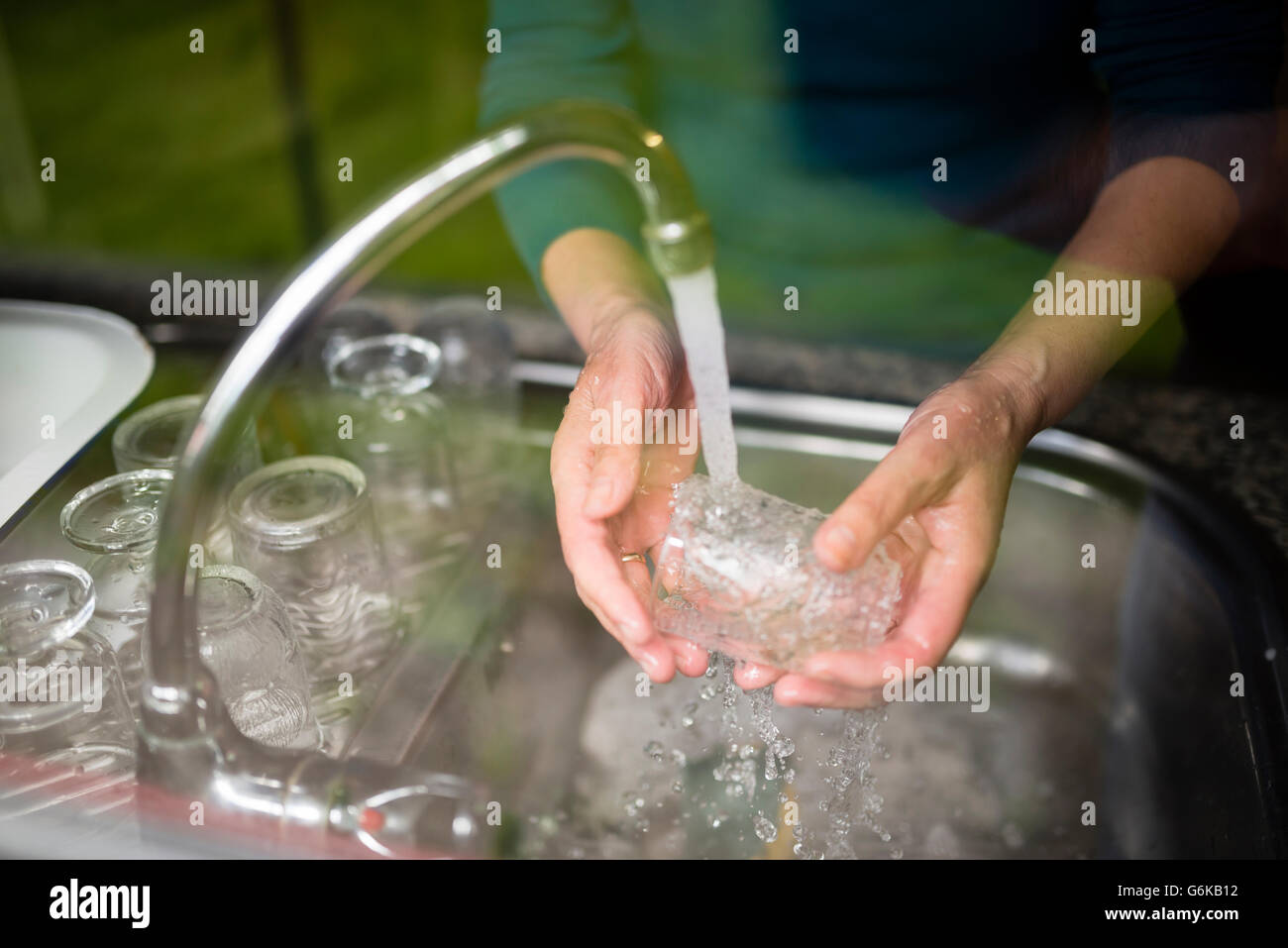 Woman washing glasses at kitchen sink Stock Photo - Alamy