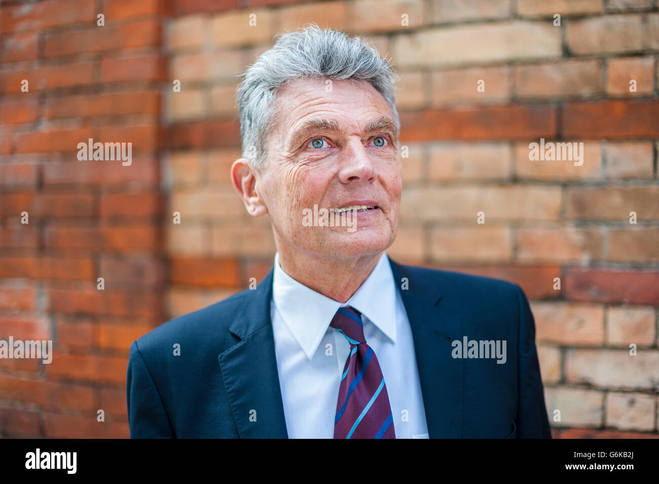Senior businessman at brick wall looking up Stock Photo - Alamy