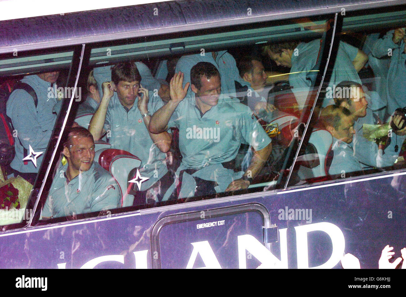 Members of the England Rugby squad wave from their coach, after ...